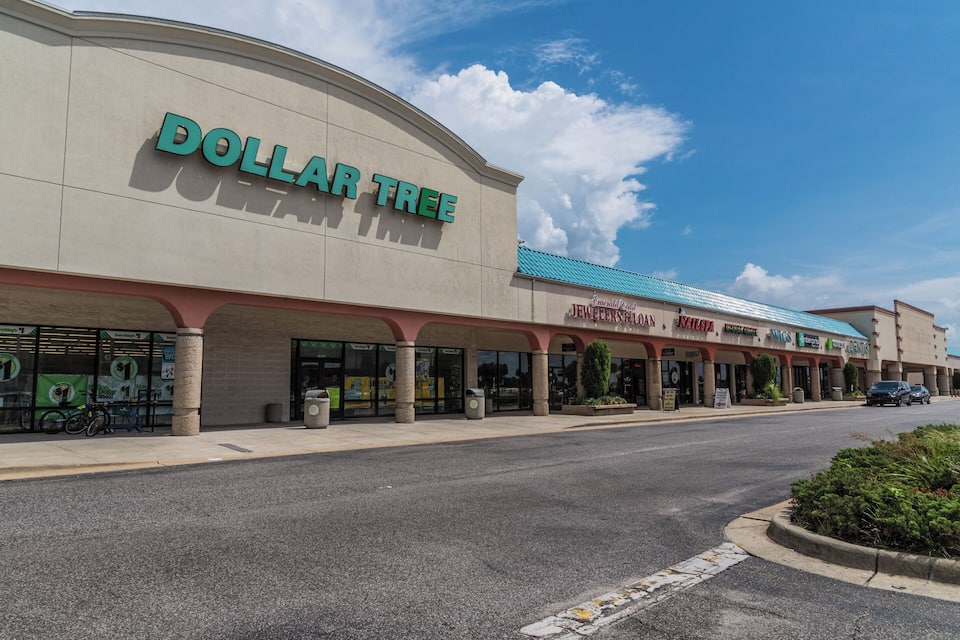 Uma loja Dollar Tree com teto azul e estabelecimentos vizinhos.