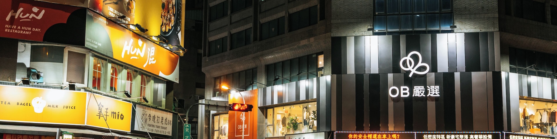 Ruas movimentadas da cidade à noite, com letreiros luminosos e vitrines iluminadas.