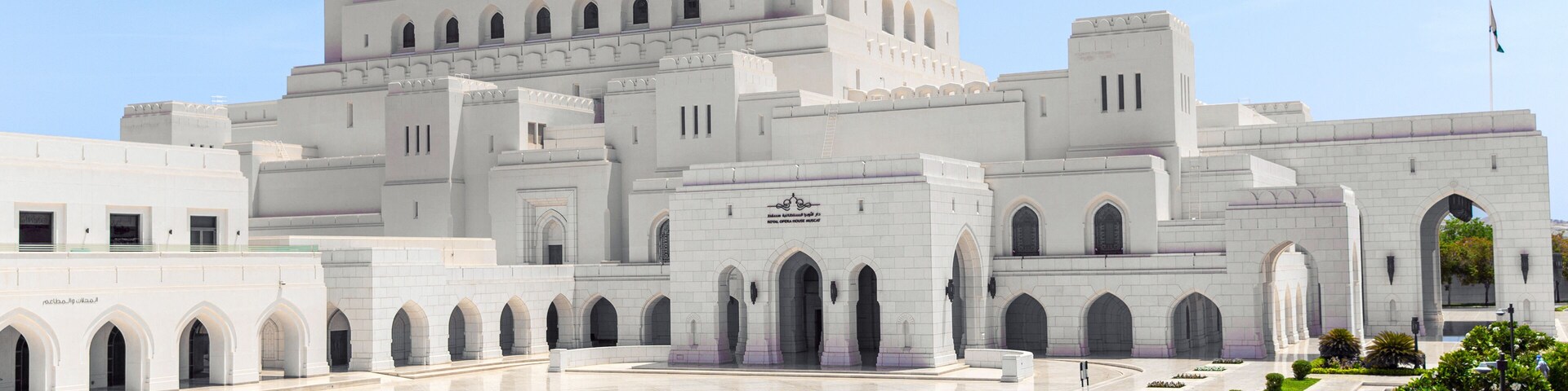 Um edifício grande e branco com várias arcadas e uma bandeira.