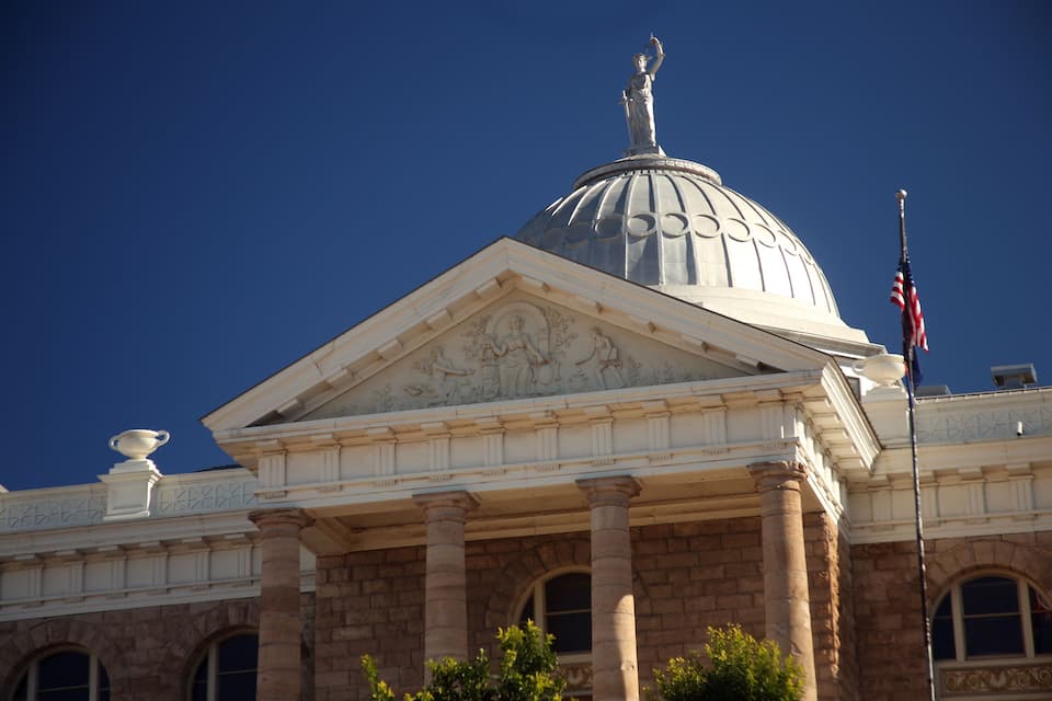 Um edifício neoclássico com uma cúpula imponente, colunas e uma estátua no topo.