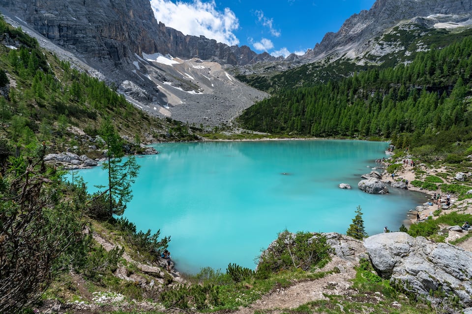 Um lago azul-turquesa rodeado por montanhas e florestas densas.