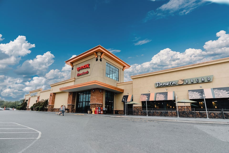 Um centro comercial com lojas como 'Max Home' e 'Panera Bread'.