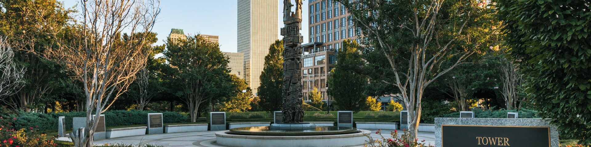 Parque com uma escultura, uma fonte e uma placa que diz 'Tower of Reconciliation'.