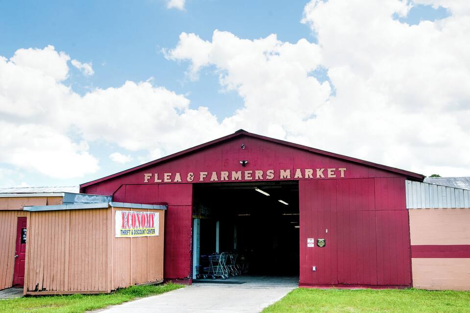 A red building labeled "Flea & Farmers Market" with a sign for "Economy Thrift & Discount Center" on the side.
