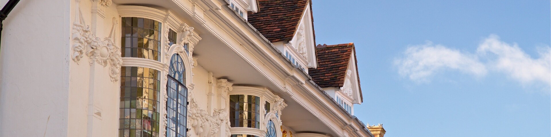 Um edifício com fachadas brancas elaboradas, várias janelas e telhados de telha vermelha.