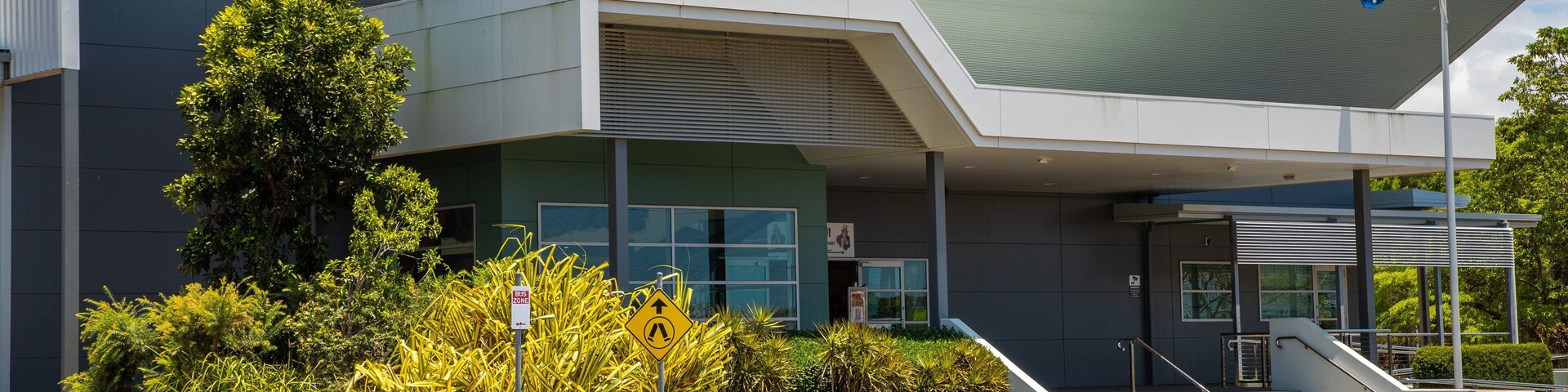 Edifício do Museu Australiano de Blindados e Artilharia, com placa, escadas e vegetação ao redor.