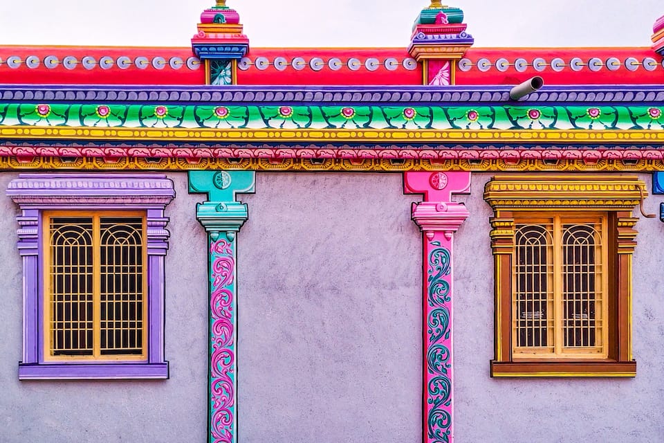 Um edifício com detalhes arquitetônicos coloridos e elaborados, incluindo molduras de janelas vibrantes e colunas decorativas.