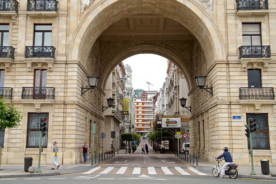 Ruas sob um arco, com edifícios em ambos os lados, uma faixa de pedestres e um ciclista.