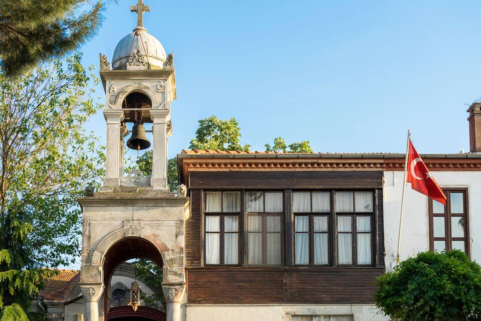 Uma igreja com uma torre de sino, uma cúpula e uma bandeira.