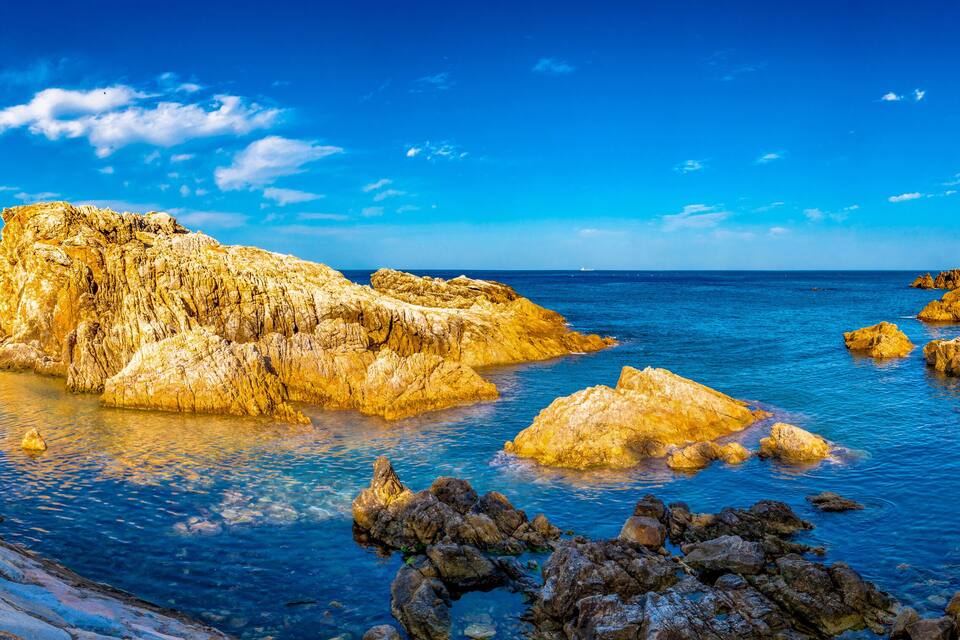 Paisagem costeira com formações rochosas e águas azul-claras.