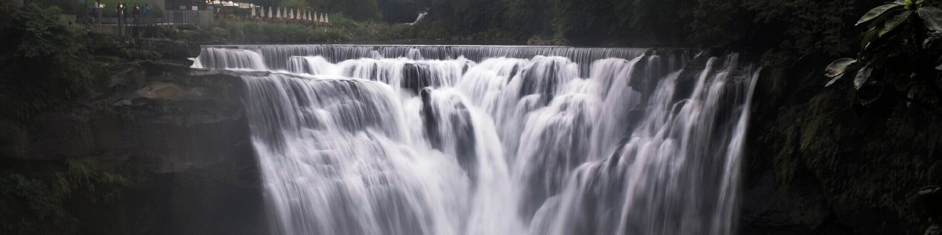Uma cascata em vários níveis, rodeada por uma floresta densa.