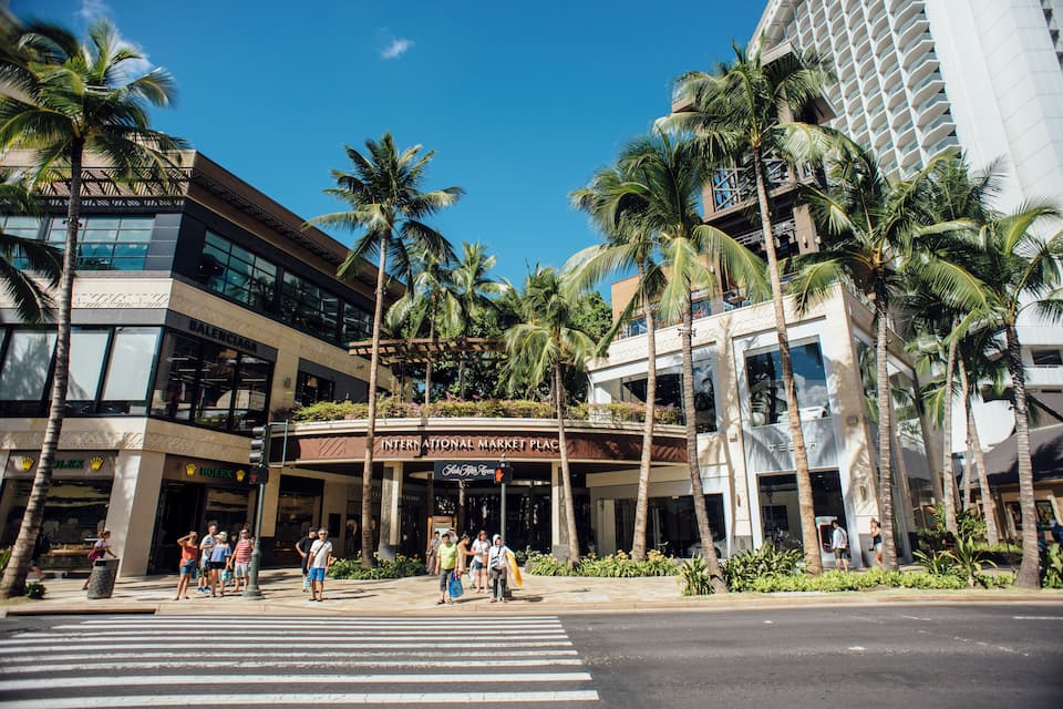 Uma área comercial com palmeiras e um edifício com a placa que diz "International Market Place".