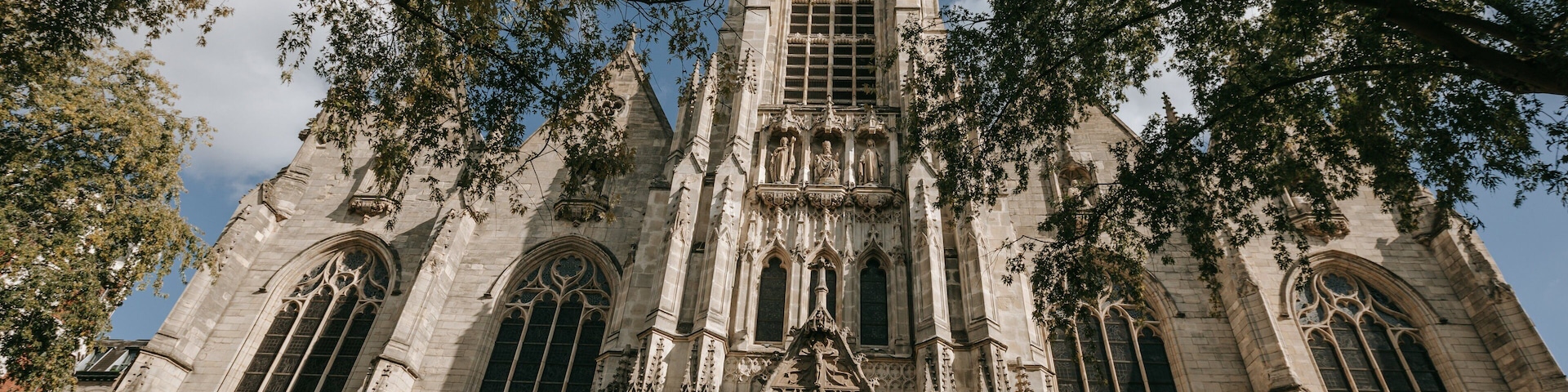 Uma catedral gótica com detalhadas esculturas em pedra, grandes janelas em arco e uma imponente agulha.