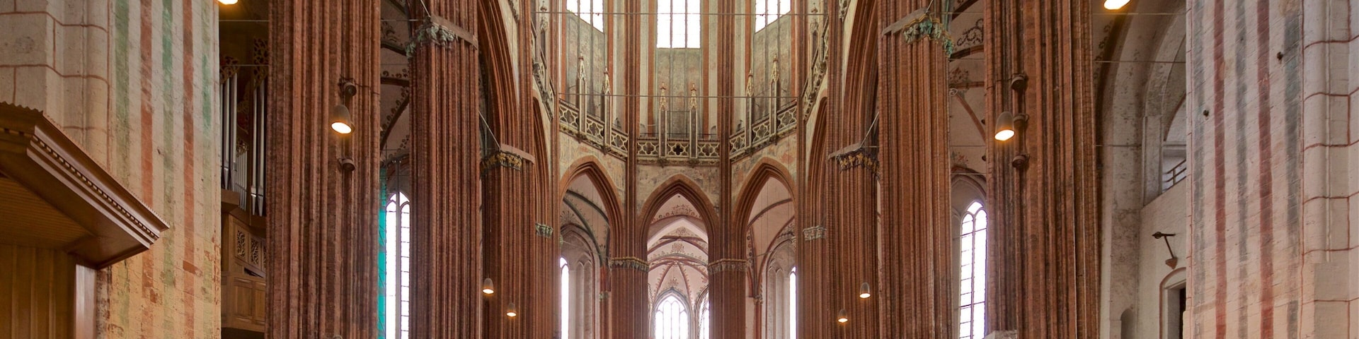 Interior de uma catedral com janelas altas e arqueadas e um altar central.