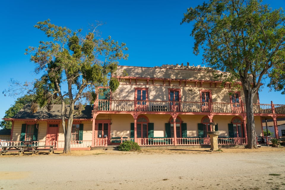 Um edifício histórico com fachada rosa, persianas verdes e uma varanda.