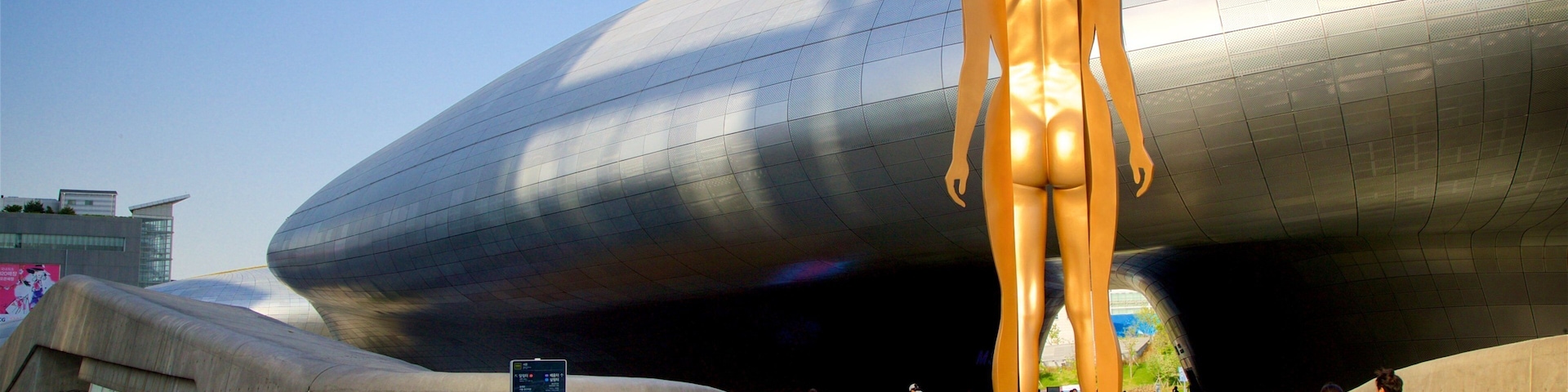 Dongdaemun Design Plaza mostrando arquitetura moderna e arte ao ar livre assim como um pequeno grupo de pessoas