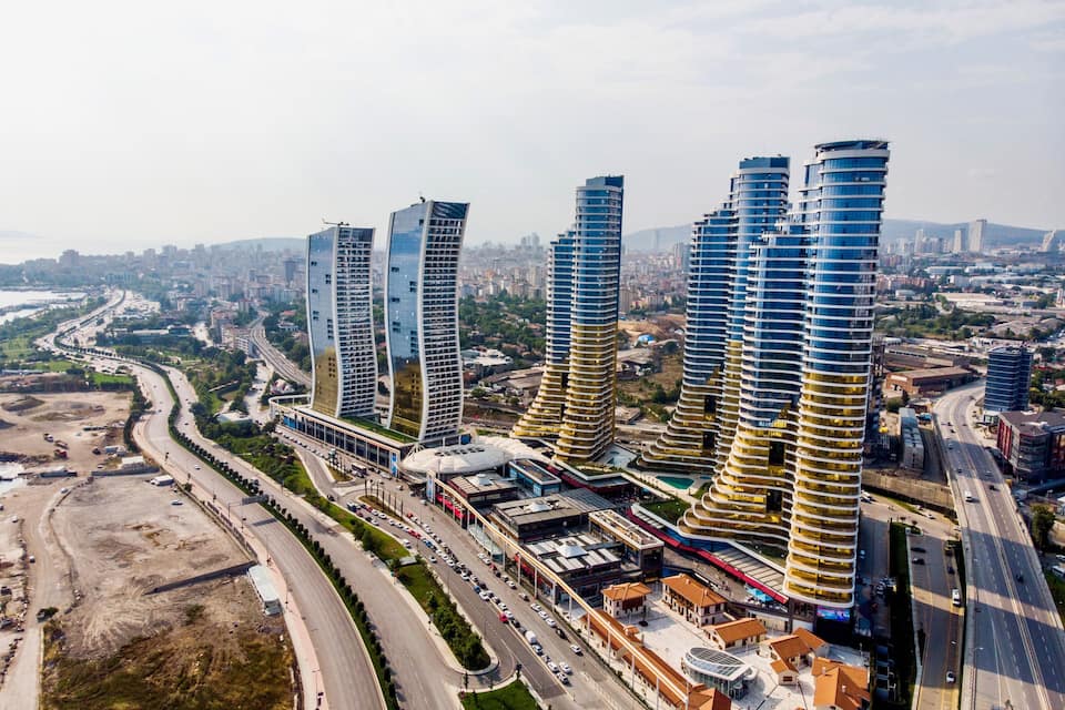 Paisagem urbana com arranha-céus modernos, uma autoestrada e um rio.