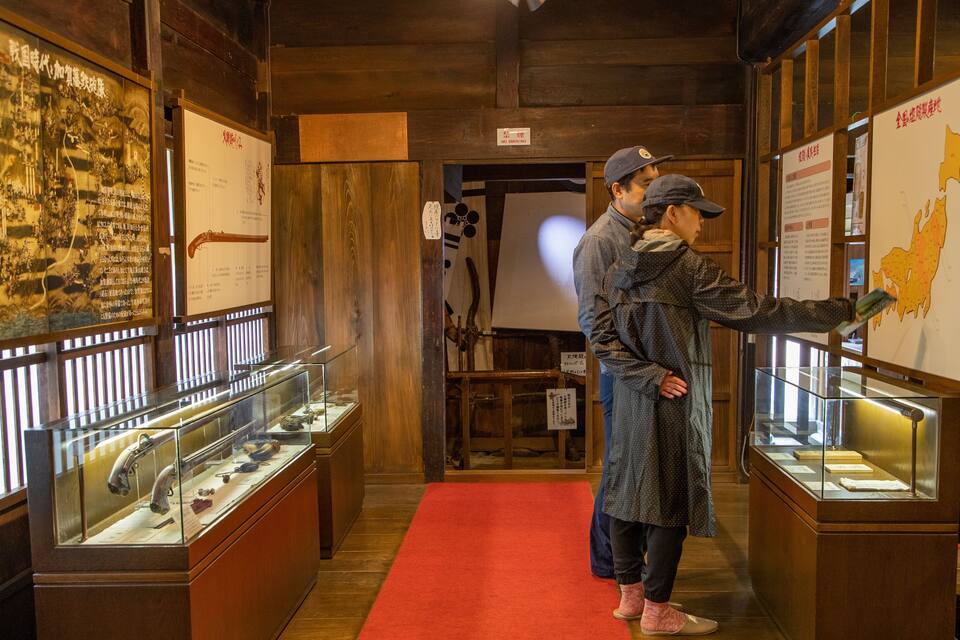 Uma pessoa analisando um mapa em um museu com interiores de madeira e vitrines de vidro.
