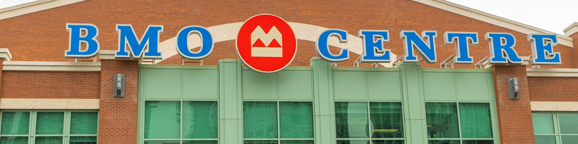Um edifício com uma placa que diz "BMO CENTRE" e um logotipo circular vermelho com um desenho de montanha.