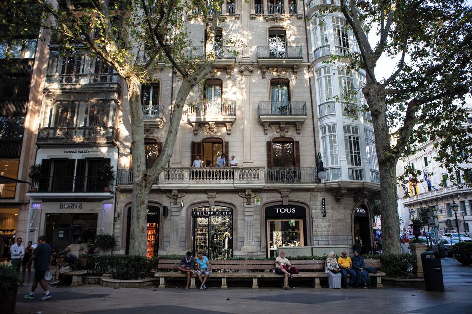 Um edifício histórico com arquitetura ornamentada, com lojas como 'BORN 8' e 'PHILIPP PUBL'.