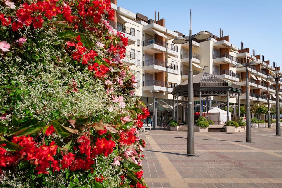 Uma parede de flores, um gazebo e um edifício de vários andares.
