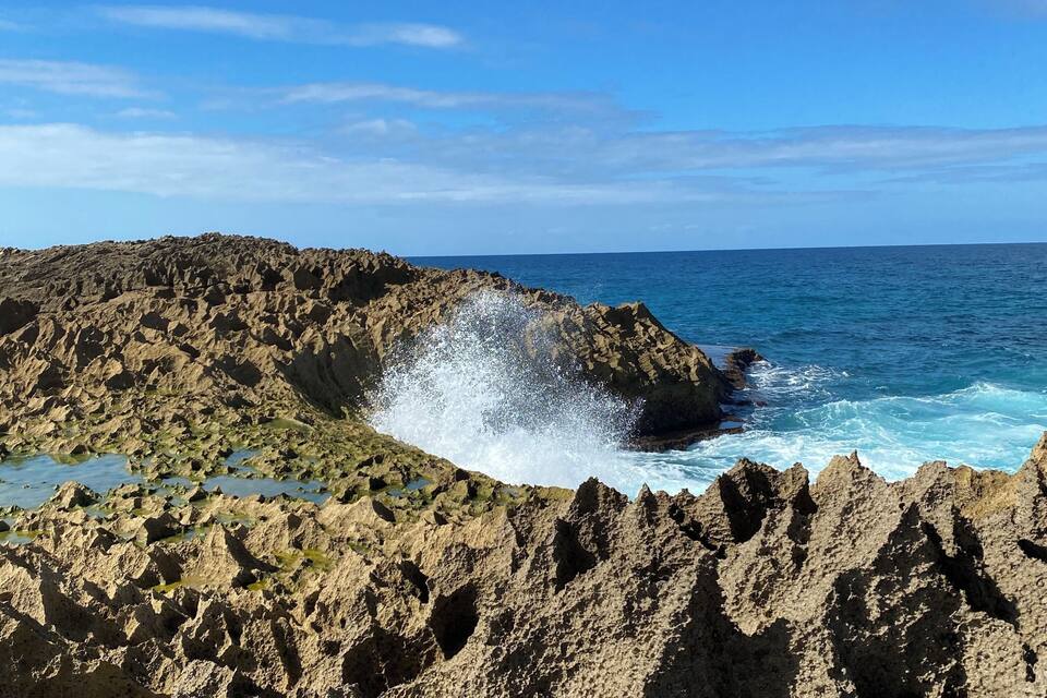 Uma costa rochosa com ondas quebrando nas pedras.