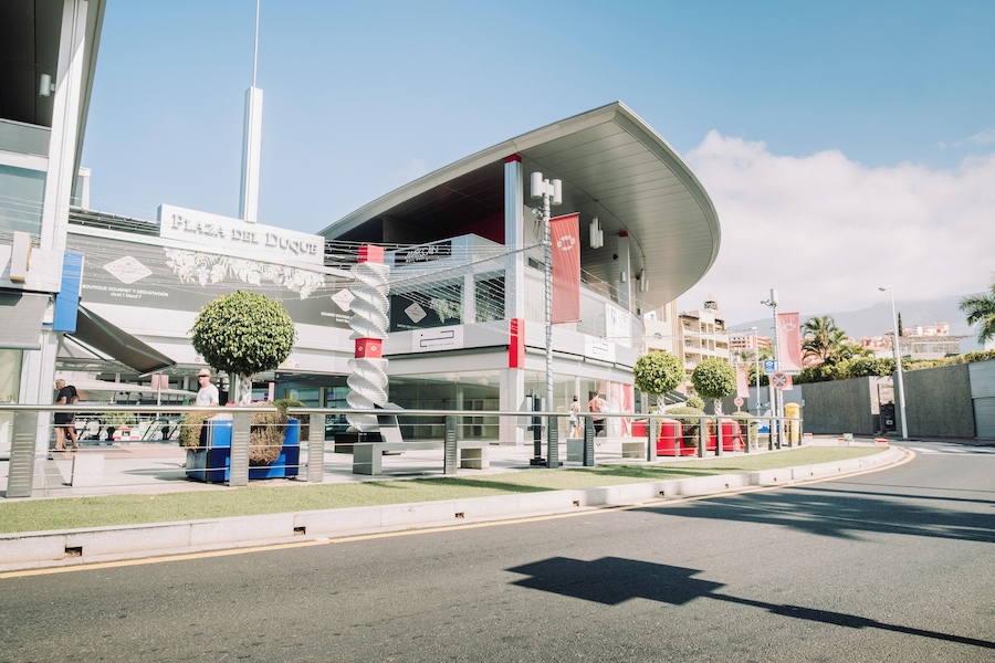 Um edifício moderno com telhado curvo e letreiro com a inscrição 'Plaza del Duque'.