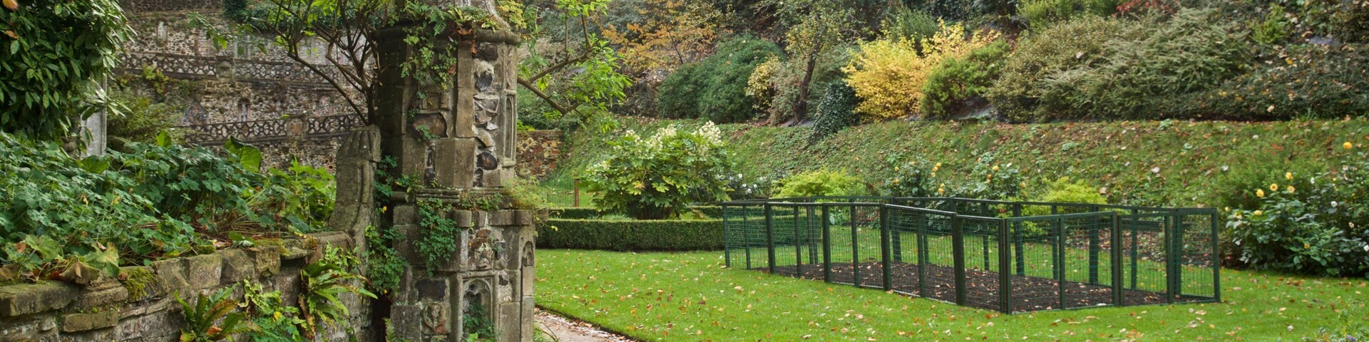 Uma construção de pedra histórica rodeada por vegetação exuberante e um jardim bem cuidado.