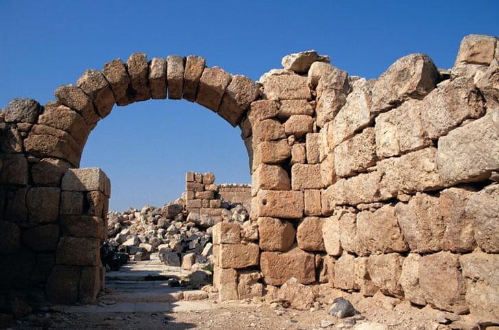 Ruínas de pedra antigas com uma grande estrutura em arco.