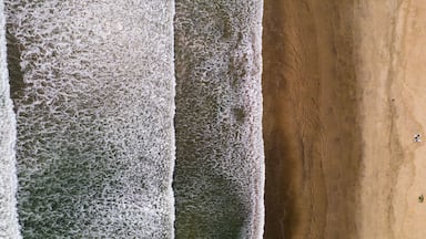 Uma praia arenosa com ondas quebrando na costa.