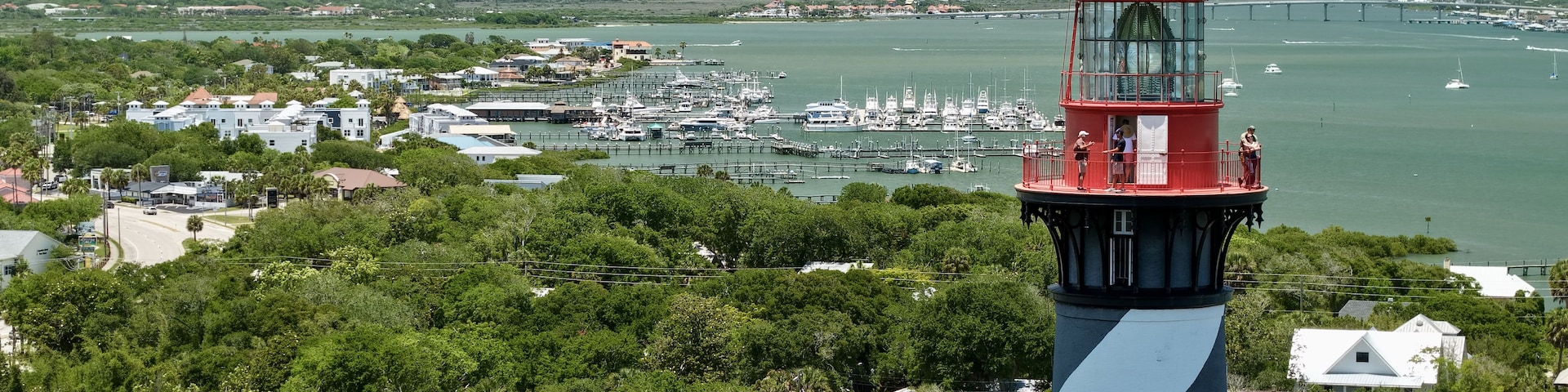 Um farol, um porto de recreio e uma vila costeira com barcos.