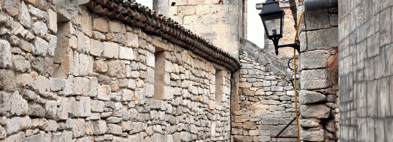 Um estreito beco de pedra com uma torre de sino ao longe.