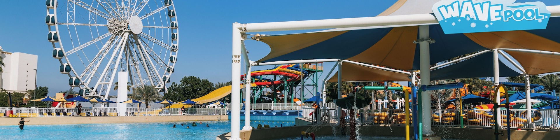 Um parque aquático com uma grande roda gigante, uma piscina de ondas e uma atração Duplo Wave Pool.