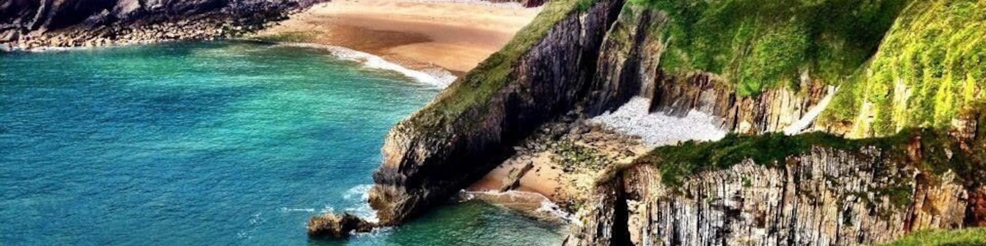 Welsh coastal path-Pembrokeshire in South Wales. The bigger beach in the back is only accessible by swimming from the smaller beach in the foreground, or by a hole in the huge rock barrier, only passable at low tide. Early August is a good time to go. It's always been warm (for Wales) and sunny at least 90% of the times I've spent down there. (Pic from August 2014). #beach