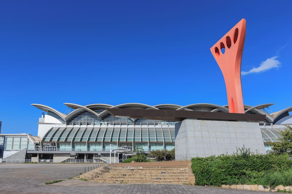 Um edifício moderno com uma escultura laranja marcante e arquitetura curvilínea.