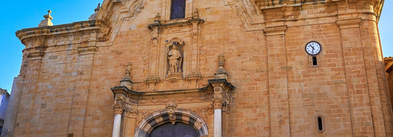 Uma igreja histórica com uma torre de sino e uma grande entrada em arco.