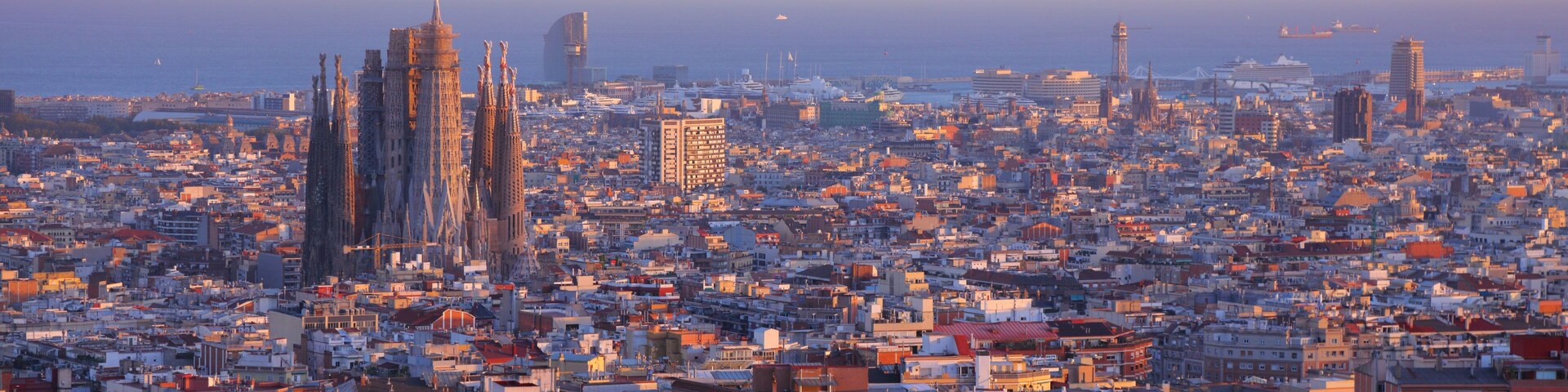 Vista panorâmica de um horizonte urbano com um edifício modernista imponente, arquitetura urbana densa e uma costa ao fundo.