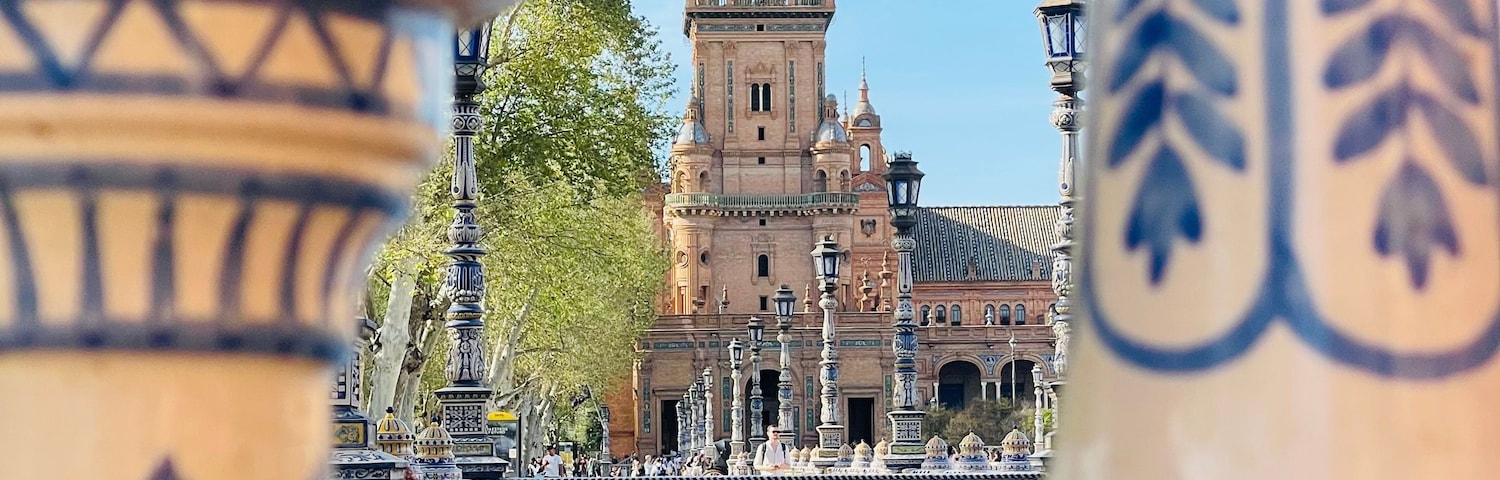 Um edifício histórico com uma torre alta e uma ponte com grades elaboradas.