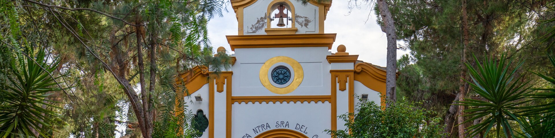 Uma igreja com um campanário, rodeada por vegetação exuberante.