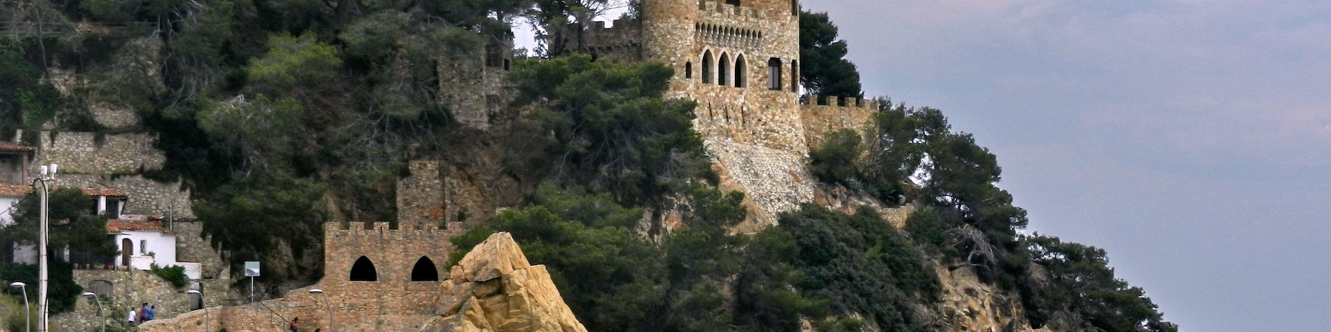 Um castelo à beira-mar, sobre um penhasco rochoso, com uma ponte que o liga.