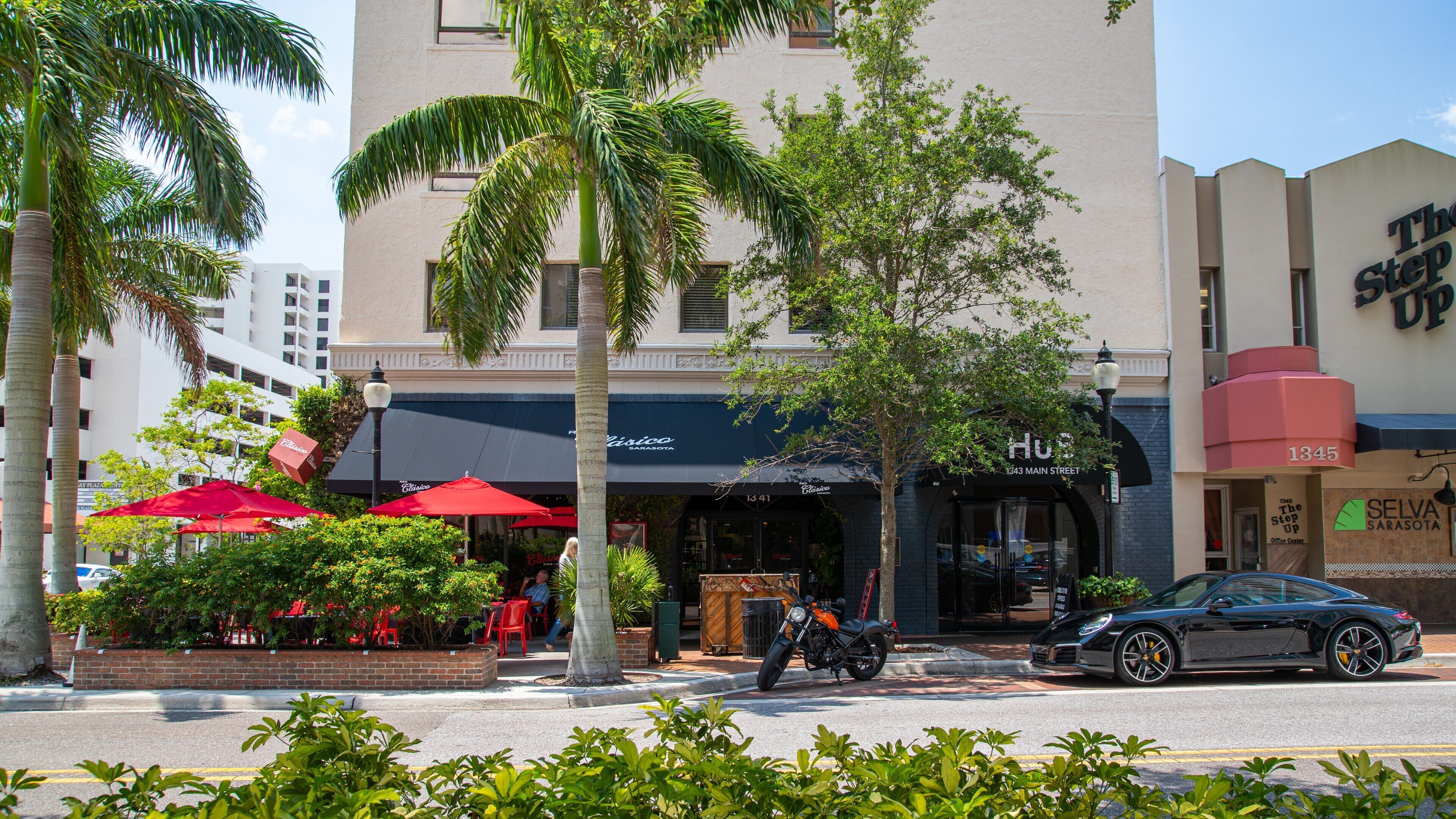 A street with a building labeled "The Step Up" and a parked black car.