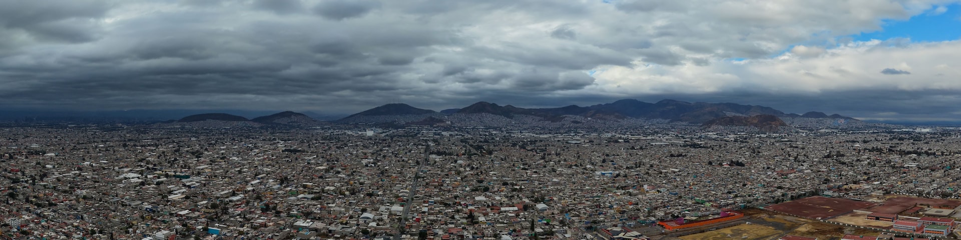 Paisagem urbana densamente povoada com uma cadeia de montanhas ao fundo.