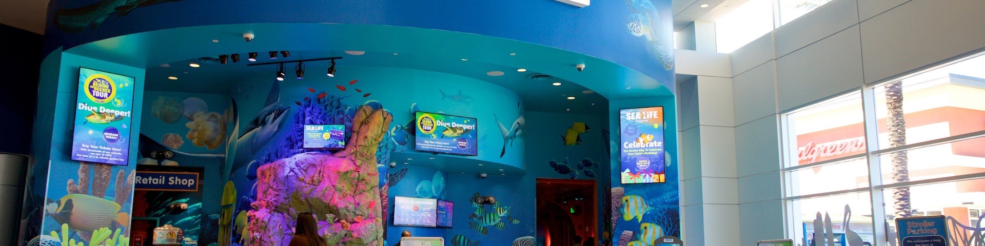 Um aquário SeaLife com uma placa grande, exibições coloridas de vida marinha e uma área para carrinhos.