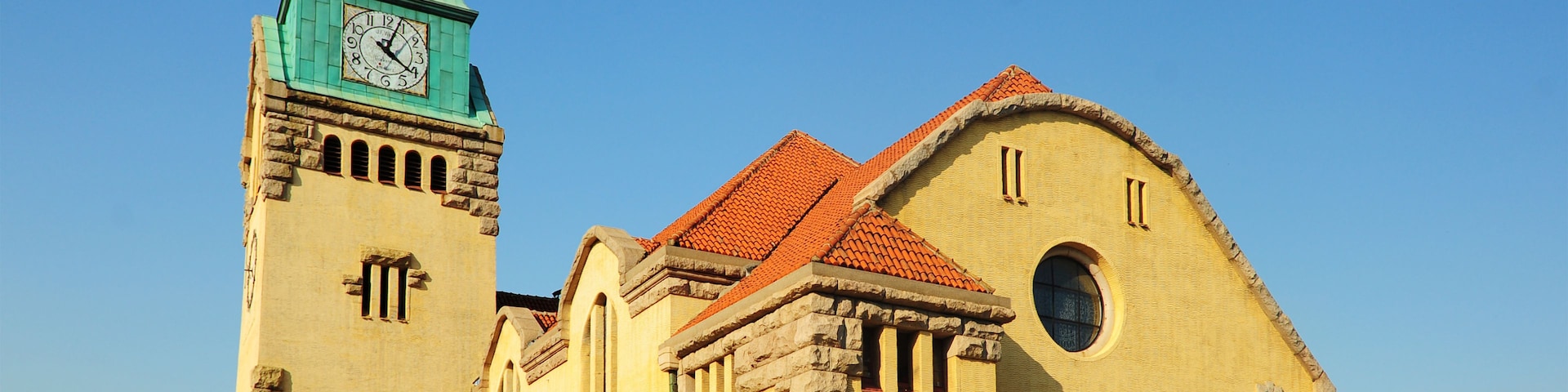 Um edifício histórico com uma torre do relógio e telhado de telhas vermelhas.