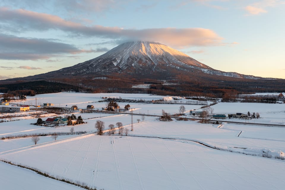 Paisagem coberta de neve com uma montanha imponente ao fundo.