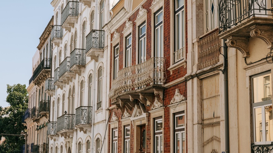 Uma fileira de edifícios históricos com varandas elaboradas e fachadas detalhadas.