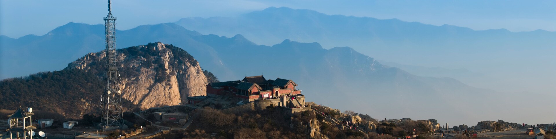Paisagem montanhosa com edifícios tradicionais e uma torre imponente.