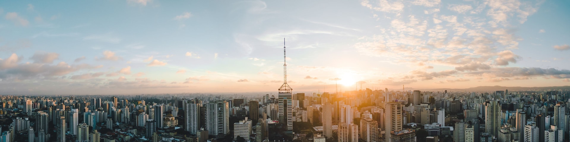 Paisagem urbana com uma torre imponente e um pôr do sol.
