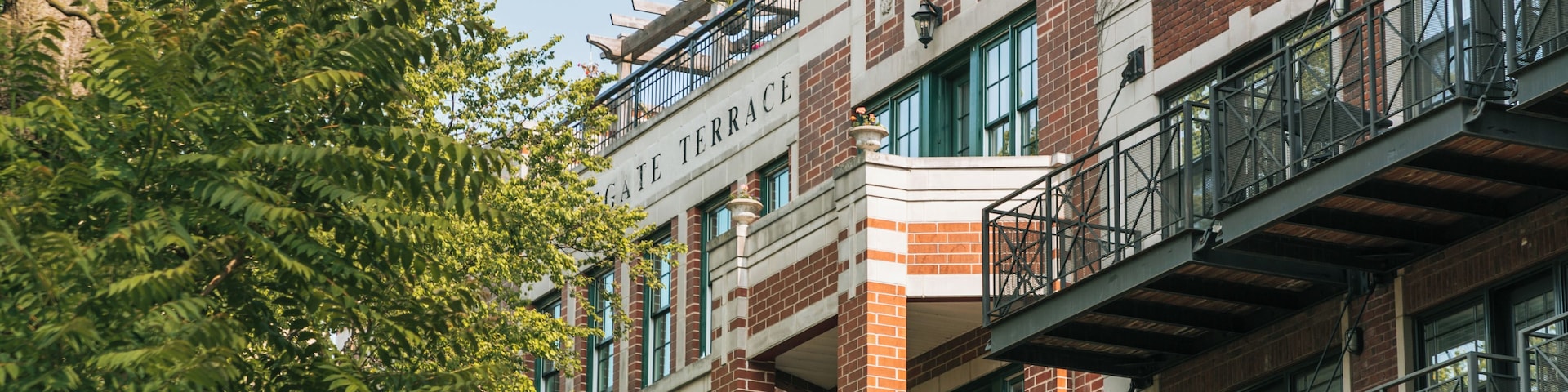 Um edifício com a placa 'GATE TERRACE' na fachada, rodeado por árvores.