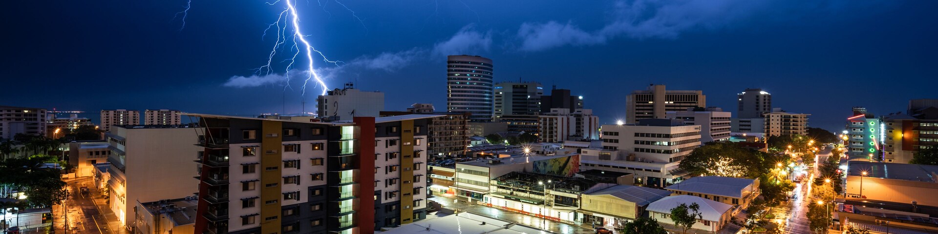 Paisagem urbana noturna com relâmpagos no céu.